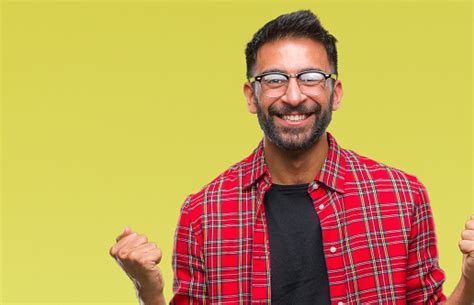 축 하 하는 고립 된 배경 위에 안경 착용의 히스패닉 남자 성인 개는 놀라게 하 고 무기와 성공을 위한 제기 및 오픈 눈 깜짝