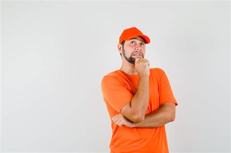 Free Photo Delivery Man Looking Up While Holding His Chin In Orange T
