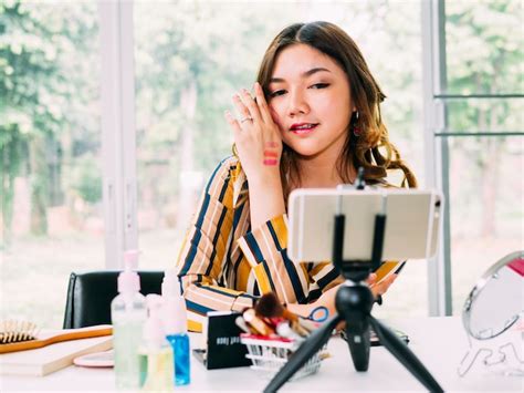 premium photo blogger with beauty products looking at mobile phone on