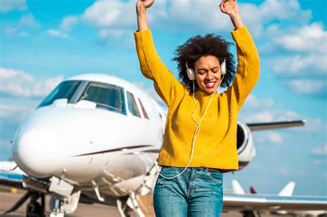 젊은 여자는 공항 활주로에 주차 된 개인 비행기 앞에서 헤드폰을 통해 재생 되는 음악의 리듬에 춤 비행기에 대한 스톡 사진 및 기타 이미지 Istock