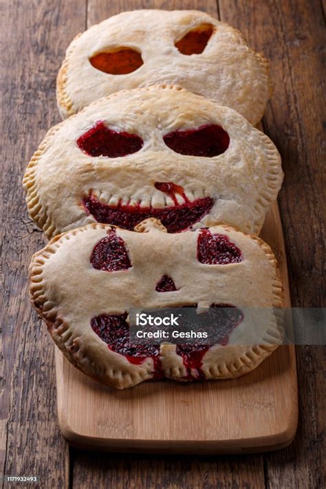 조각 무서운 얼굴 파이 해피 할로윈 조리법 빨간 열매를 곁들인 홈메이드 케이크 2개와 나무 테이블에 호박 타르트 1개 3가지