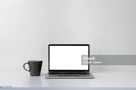 복사 공간을 위한 흰색 배경에 사무실 책상 테이블에 빈 스크린 노트북 컴퓨터와 커피 컵이 있는 현대적인 현대 업무 공간 홈