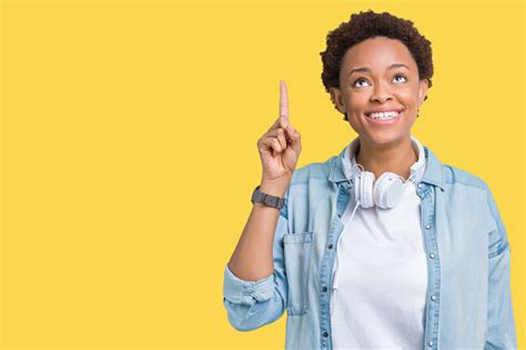 성공적인 아이디어를 고립 된 배경 가리키는 손가락에 헤드폰을 입고 젊은 아프리카계 미국인 여자 종료 하 고 행복 번호 하나입니다 가리키기에 대한 스톡 사진 및 기타 이미지