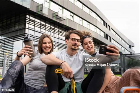 사람들의 그룹 남성과 여성 남성과 여성 현대 친구 오픈 체육관에 앉아 훈련 전후에 현대 야외 피트니스 파크 휴대 전화 복사 공간으로 셀카 사진을 찍습니다 16 17 살에