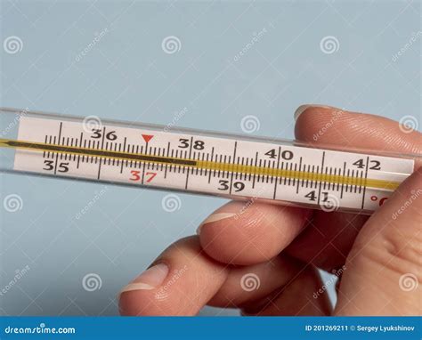 Mercury Thermometer In The Hand Of A Woman On A Blue Background Temperature Measurement Using A