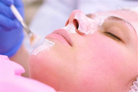 미용사 전문의는 브러쉬로 여성의 얼굴에 마스크를 넣습니다 보습 얼굴 얼굴을 클로즈업합니다 2명에 대한 스톡 사진 및 기타 이미지