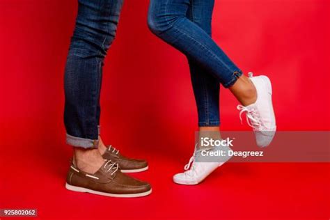 여자와 남자 다리 청바지 바지와 신발 제기 다리 세련 된 몇 날짜 동안 키스와 여자의 근접 촬영 사진 고립 된 빨간 배경 그는 대 위에 그녀 신발에 대한 스톡 사진 및 기타