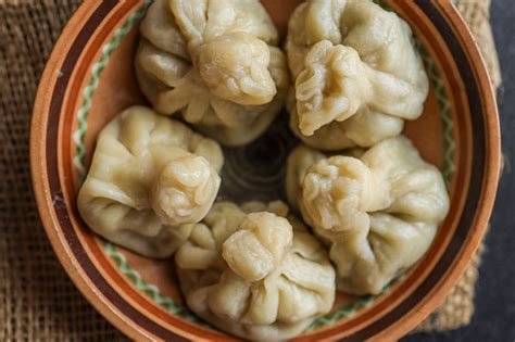 수제 도자기 그릇에 담긴 전통 찐 만두를 클로즈업한 모습 만두는 소박한 삼베 천에 깔끔하게 정리되어 진열되어 주름진 반죽