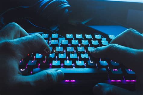 Male Hands Typing On The Black Illuminated Keyboard With Blue Light