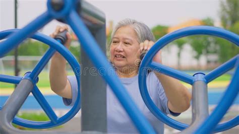 Senior Asian Woman In Casual Workout In Exercise Stations In Public