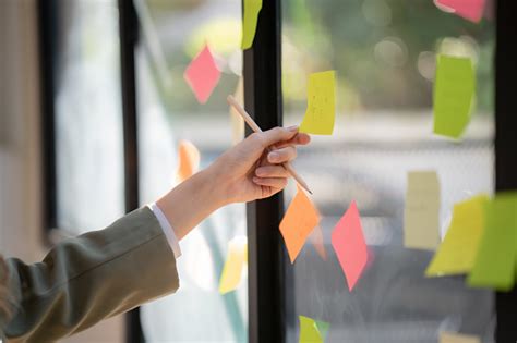 유리 벽에 포스트잇을 사용하여 개발이 성공으로 성장하기 위한 전략적 사업 계획을 작성하는 사업가의 손 결정에 대한 스톡 사진 및