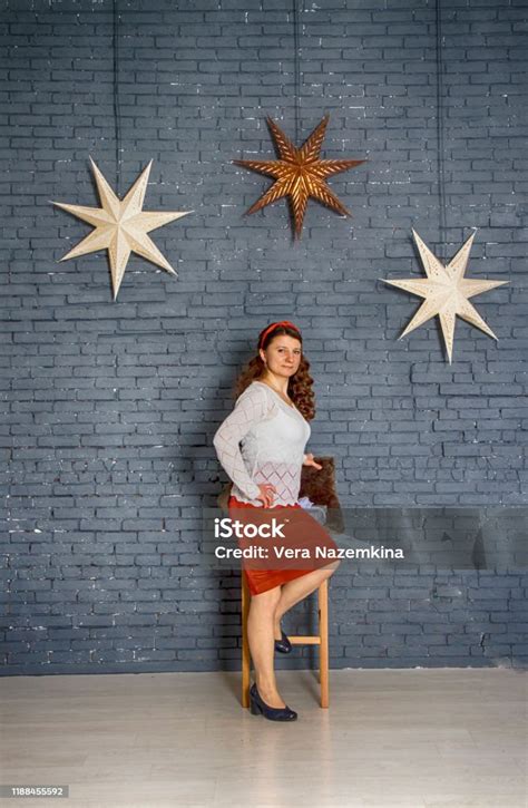 빨간 테두리와 치마를 입은 젊은 여성은 파란색 벽돌 벽을 배경으로 높은 의자에 기대어 있습니다 스튜디오 샷 Screening에 대한 스톡 사진 및 기타 이미지 Istock