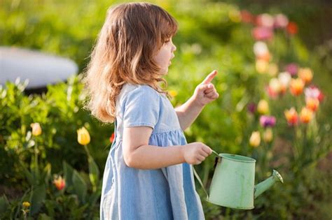 人物 摄影 品牌 浇水 外国小女孩 连衣裙 蓝色 天然绿色 郁金香 水仙花 光影 光效 侧脸 金发 水壶 室外 花园 草地 夏天