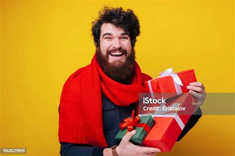 빨간 스카프에 잘 생긴 수염 남자 선물 상자를 들고 판매 개념 선물을 즐기는 고립 된 노란색 배경 공예에 대한 스톡 사진 및