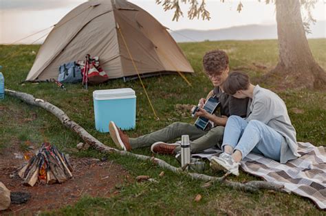 산속의 캠핑장에서 행복한 쾌활한 커플 여자 친구를 위해 기타를 연주하는 남자 20 24세에 대한 스톡 사진 및 기타 이미지 20 24세 계곡 관광 Istock