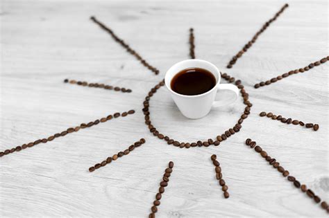 나무 배경에 태양의 형태로 접힌 커피 곡물 중간에 커피 한 잔 그것은 일출 후 커피를 마시는 시간을 의미 0명에 대한 스톡 사진 및 기타 이미지 Istock