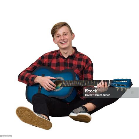 흰색 배경 위에 고립 된 바닥에 앉아 어쿠스틱 기타에서 연주 재능있는 소년 십대의 전체 길이 초상화 학생들이 유명한 뮤지션이 될 수있는 훌륭한 음악 수업 가수에 대한 스톡