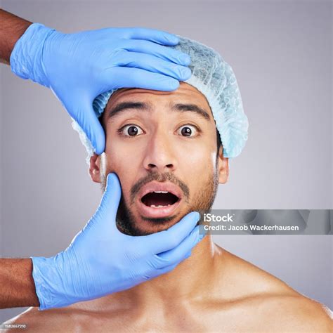 남자 손 얼굴은 스튜디오에서 성형 수술을 위해 두려움 고통 배경으로 화장품을 두려워합니다 의사 장갑 피부과 의사 및 와우 놀라움 및 얼굴 변형을 가진 환자 20 24세에