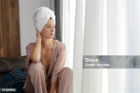 흰 수건과 실크 가운으로 머리를 감싼 젊은 아름 다운 여자가 아파트의 창문 옆에서 아침을 즐기고 있습니다 40 44세에 대한 스톡 사진 및 기타 이미지 Istock