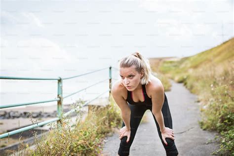 검은 운동복을 입은 젊은 스포티 한 여성 러너가 바닷가에 서서 쉬고 있습니다 공간을 복사합니다 사진 Unsplash의