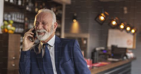 현대적인 사무실 건물 레스토랑 카운터 옆에 서서 전화 대화를 나누는 고위 사업가 사진 Unsplash의 세르비아 이미지