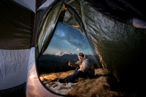 Male Tourist Have A Rest In His Camping In The Mountains At Night Under