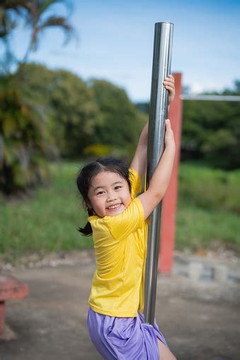 활기찬 야외 놀이터에서 반짝이는 금속 기둥에서 놀고 햇볕이 잘 드는 환경에서 행복과 활기찬 에너지를 보여주는 즐거운 아시아 어린이 6 7 살에 대한 스톡 사진 및 기타