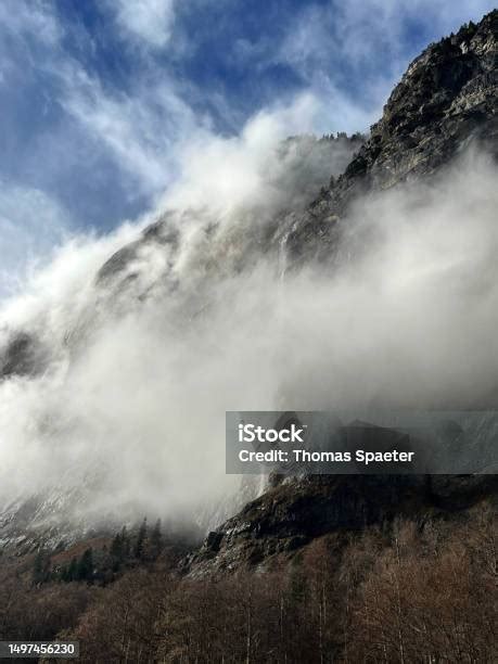 아침 안개가 솟아오르는 스위스 알프스의 가파른 바위 절벽에서 떨어지는 신비한 폭포 구름 뒤로 물이 떨어지는 스위스의 산맥 단일