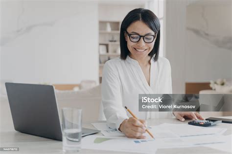 안경을 쓴 웃는 사업가는 노트북으로 사무실 책상에 앉아 프로젝트 예산을 계산하는 일을 한다 30 34세에 대한 스톡 사진 및 기타 이미지 30 34세 갈색 머리