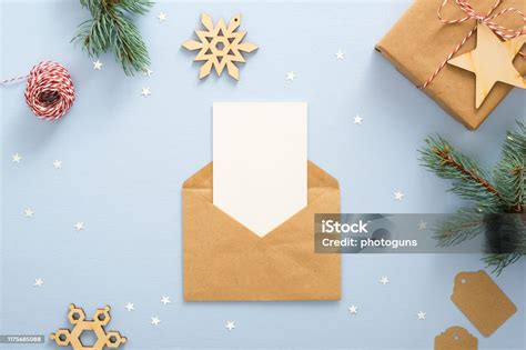 색종이 스타 선물 상자 나무 눈송이 전나무 나무 가지로 장식 파스텔 블루 배경에 크래프트 종이 봉투에 빈 카드 크리스마스 새해 겨울 휴가 초대 모형 0명에 대한 스톡 사진