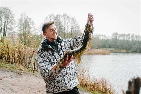 행복 한 쾌활 한 젊은 어부의 호수와 자연의 배경에 큰 물고기 파이크를 개최 합니다 낚시 배경입니다 좋은 캐치 트로피 물고기 낚시꾼 헤드샷 닫습니다 강에 대한 스톡 사진 및