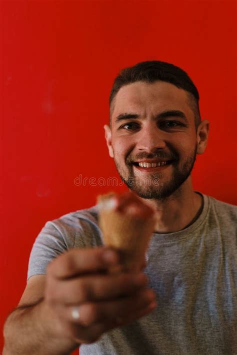 A Young Caucasian Bearded Guy Eats A Popsicle In A Cone Standing Near A