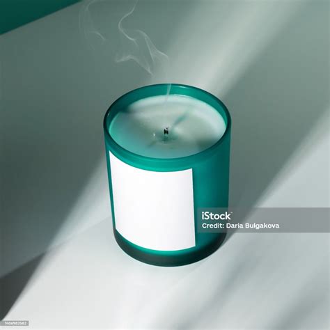 그림자가있는 아쿠아 마린 유리에 향기로운 콩 왁스 촛불 심지에서 나오는 연기와 함께 향기로운 촛불의 창조적 인 이미지 아늑한