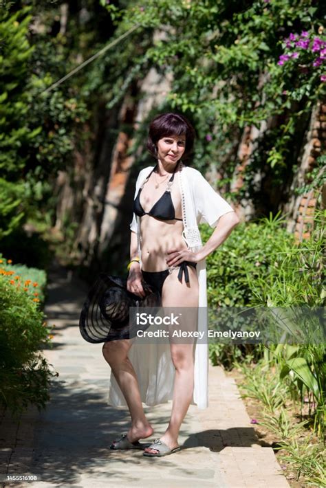 검은 수영복을 입고 녹지 사이의 좁은 길에서 모자를 쓴 젊은 여자 40 44세에 대한 스톡 사진 및 기타 이미지 40 44세 갈색 머리 건강한 생활방식 Istock