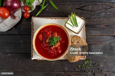 소고기와 사워 크림을 곁들인 보르슈트 사탕무 감자 시리얼 삶은 고기로 만든 전통 우크라이나 야채 수프와 나무 주방 테이블에 세라믹 그릇에 호밀 빵 두 조각 0명에 대한 스톡