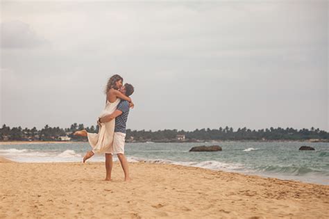 바다를 배경으로 신혼여행 여름을 즐기는 포옹에 키스하는 커플 바다 해안선의 열대 모래 해변에서 행복한 사랑스러운 커플 가족 여행 휴가 개념입니다 광고 문안 공간 복사 2명에