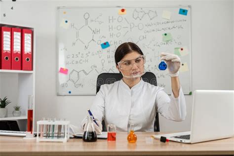 Female Scientific Laboratory Looking On Test Tube With Reagent For Experiment Stock Photo