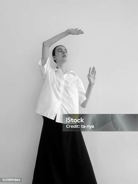 세련 된 미니멀리즘 옷을 입고 아름 다운 젊은 여자 스칸디나비아 스타일 화이트 반 소매 셔츠 긴 넓은 검은 맥시 스커트 패션 모델 포즈를 취하는 표현 자신감 있는 예쁜 패션