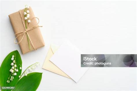 크래프트 페이퍼로 싸인 선물 또는 선물 상자 계곡의 꽃 백합 흰색 테이블에 빈 종이 카드가있는 낭만적 인 편지 플랫 레이 상단 보기 0명에 대한 스톡 사진 및 기타 이미지