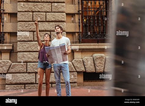 Tourist Couple Using A Map To Find Their Destination Woman Traveler Standing With A Man Holding