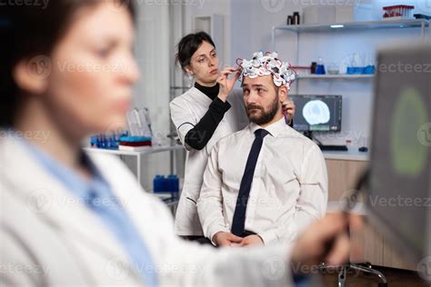 Specialist Woman In Neuroscience Adjusting Eeg Headset Analyzing Brain Activity Of Man Patient