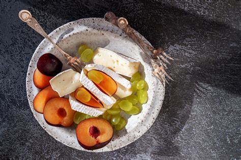 포도와 자두를 곁들인 카망베르 브리 치즈 카망베르와 브리 치즈를 한입 크기로 얇게 썬 요리 수제 접시에 치즈가 제공됩니다 평면도