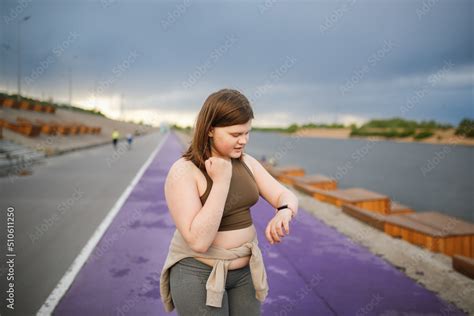 European Teenage Girl Overweight On Jog On Treadmill Along Embankment Of City Overweight And