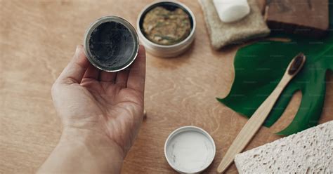 대나무 칫솔 비누 고체 샴푸 금속 면도기 녹색 몬스테라 잎이 있는 나무에 데오도란트를 배경으로 유리 병에 천연 에코 숯 치약을 들고 있습니다 폐기물 제로 사진