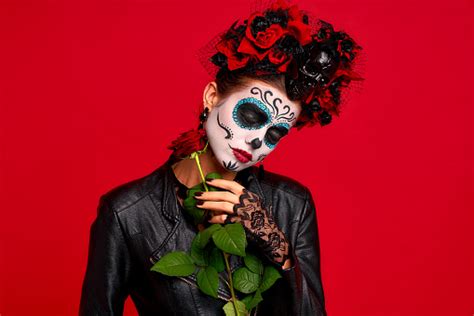 그녀의 머리와 두개골에 꽃화환과 설탕 두개골 메이크업과 로맨틱 죽은 거 빨간색 배경에 고립 된 빨간 장미를 들고 검은 장갑을 착용 할로윈 또는 칼라베라 카트리나의 개념