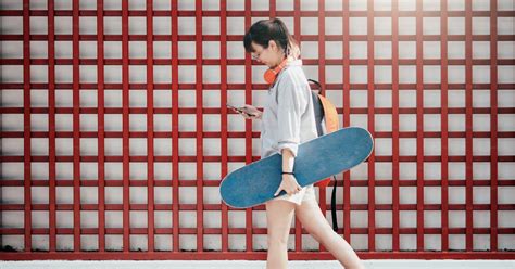 젊은 힙스터 아시아 소녀가 걷고 스케이트보드를 들고 휴대폰을 사용하여 채팅을 합니다 사진 Unsplash의 걷기 이미지