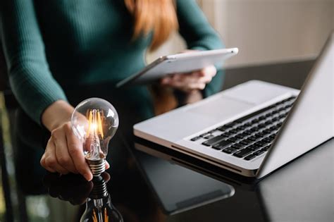 사무실에서 노트북 컴퓨터와 돈 스택을 사용하여 전구를 들고있는 비즈니스 손 아이디어 절약 에너지 및 회계 재무 개념 계산기에 대한 스톡 사진 및 기타 이미지 Istock