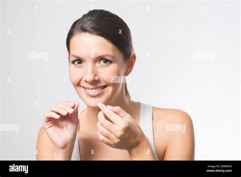 Woman Flossing Her Teeth With Dental Floss To Remove Any Food Particles Or Bacteria Caught