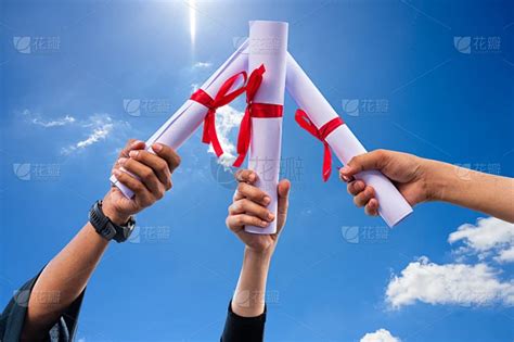 毕业生手握毕业证书卷在蓝天背景下，教育成功理念素材 花瓣网