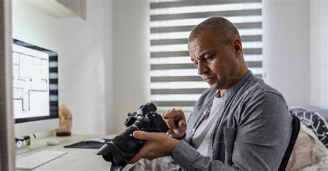 촬영 사진을 확인하세요 숙련 된 남자가 한 손에는 검은 색 전문 카메라를 들고 다른 손으로 터치 스크린의 사진을 확대합니다 사진 작가의 직업 사진 Unsplash의